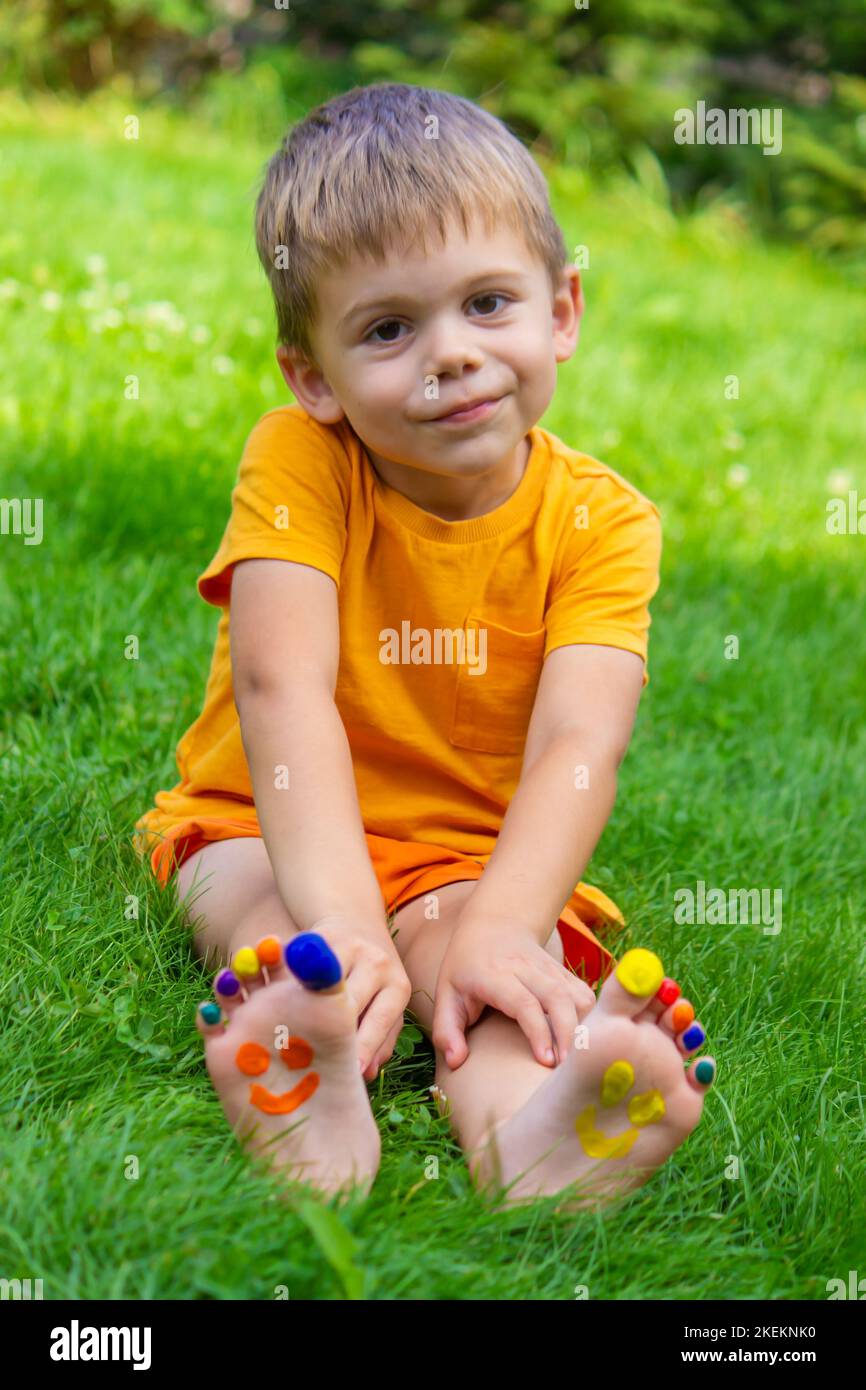 Children's feet with a pattern of paints smile on the green grass ...