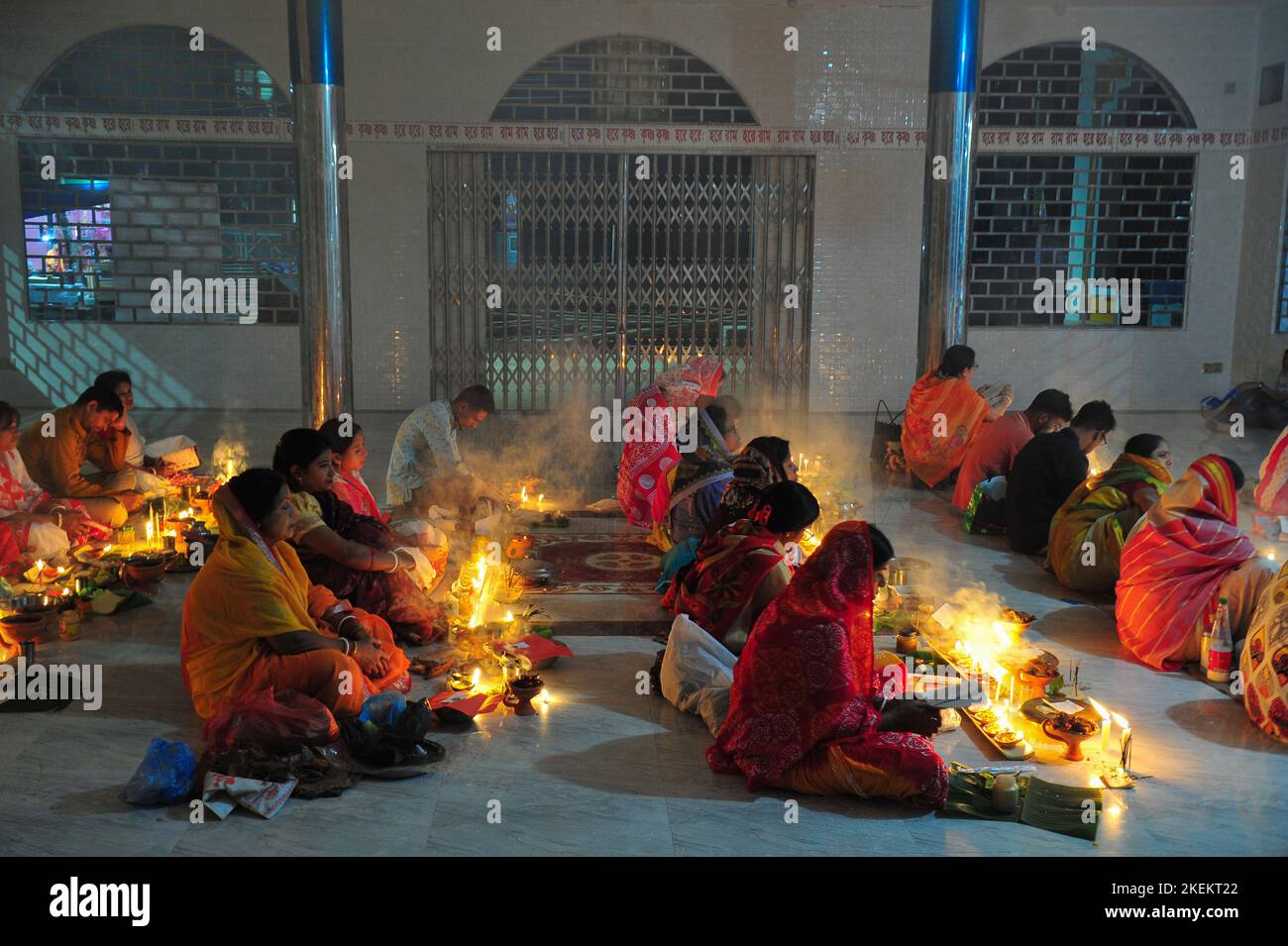 Hindu devotees sit together with lamps on the floor at Loknath Temple ...
