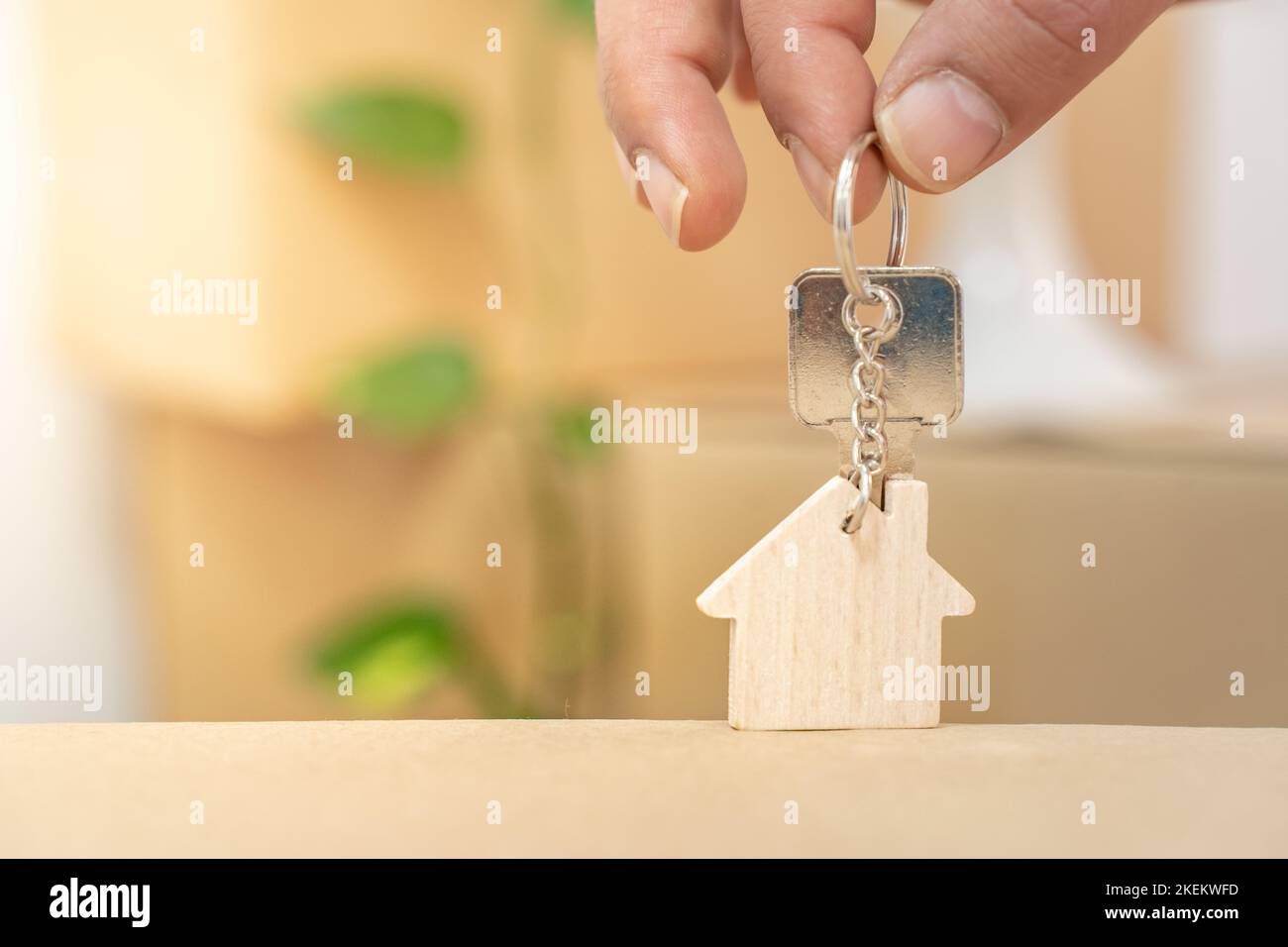 Hand holding house keys on keyring in the shape of a wooden house with ...