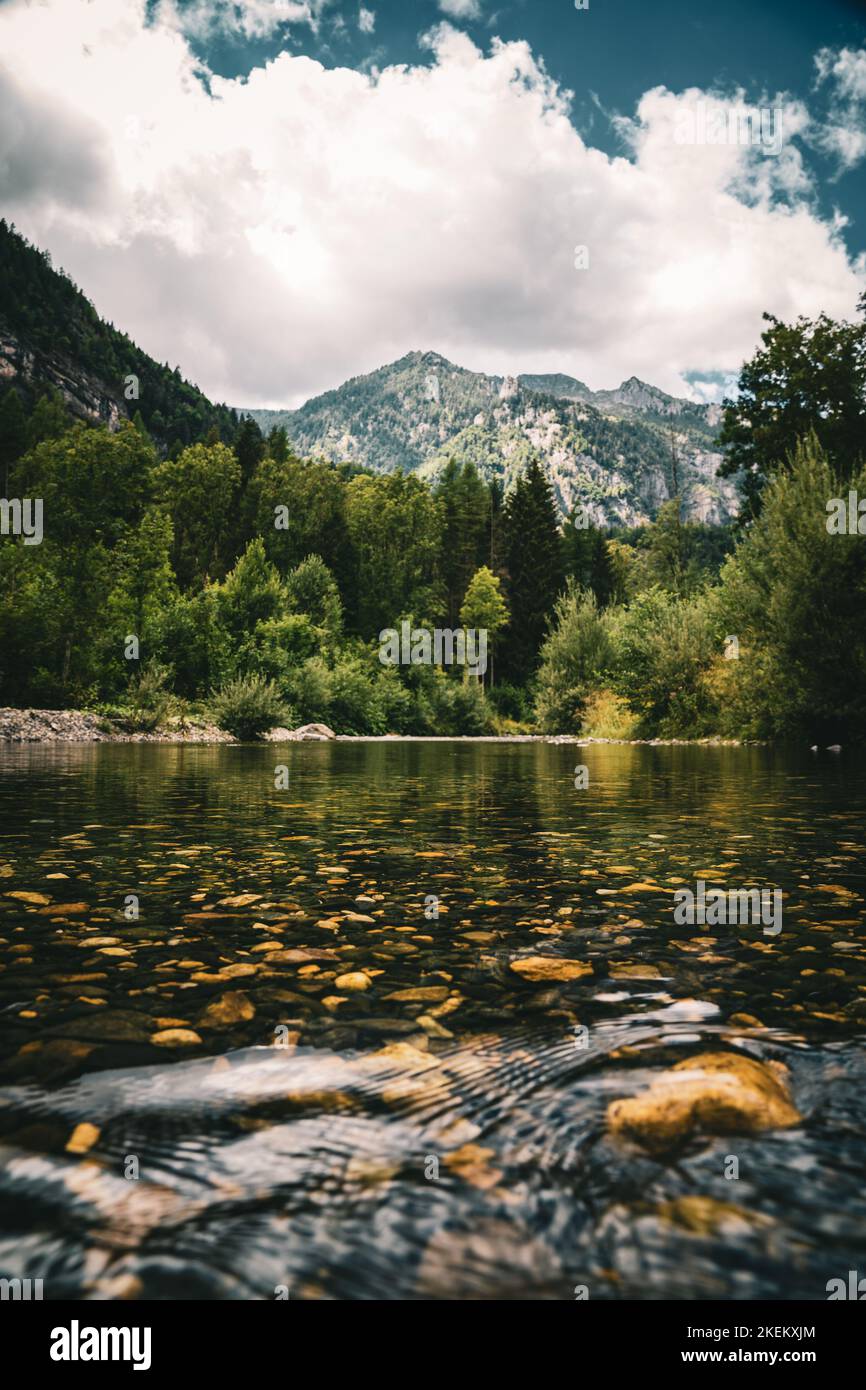 A clear lake with stones underwater and a mountain background Stock ...