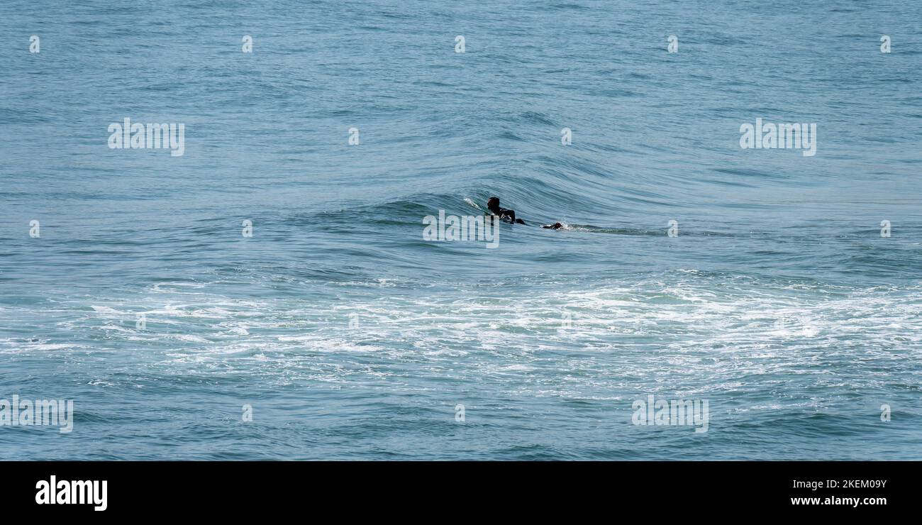 County Cork, Ireland, July 17, 2022. One male surfer is lying on a ...