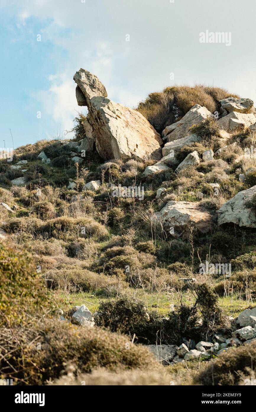 A low angle of a hill with heavy rocks and grass during the daytime ...