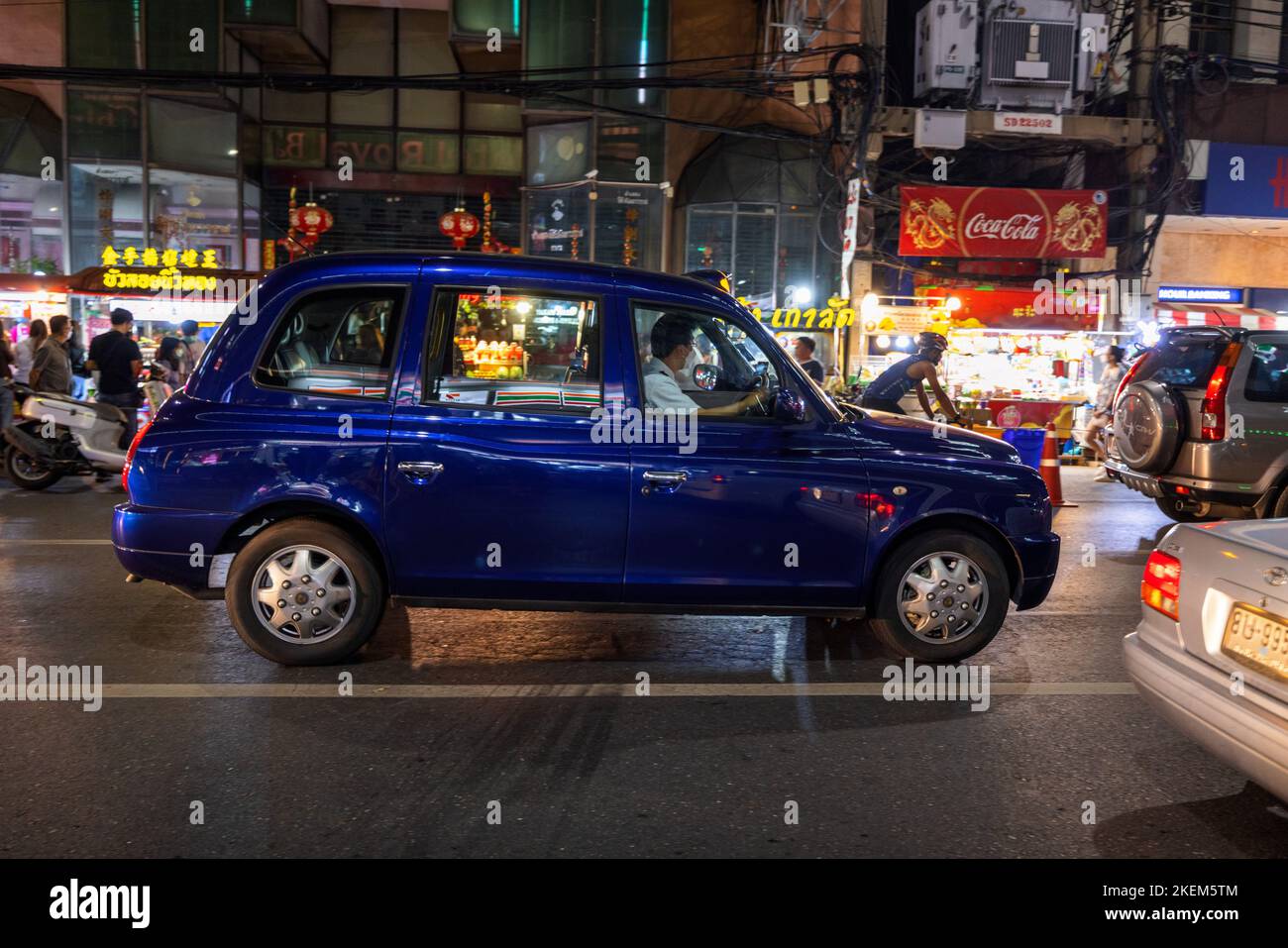 A blue taxi driving on the busy roads of the Chinatown in Bangkok ...