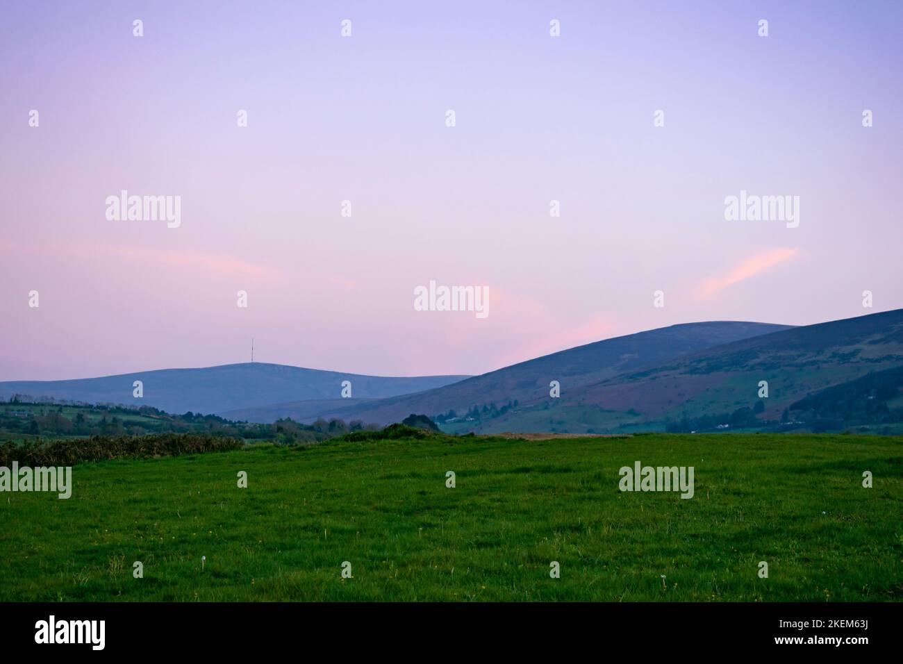 A big green field with mountains in the background against the purple ...