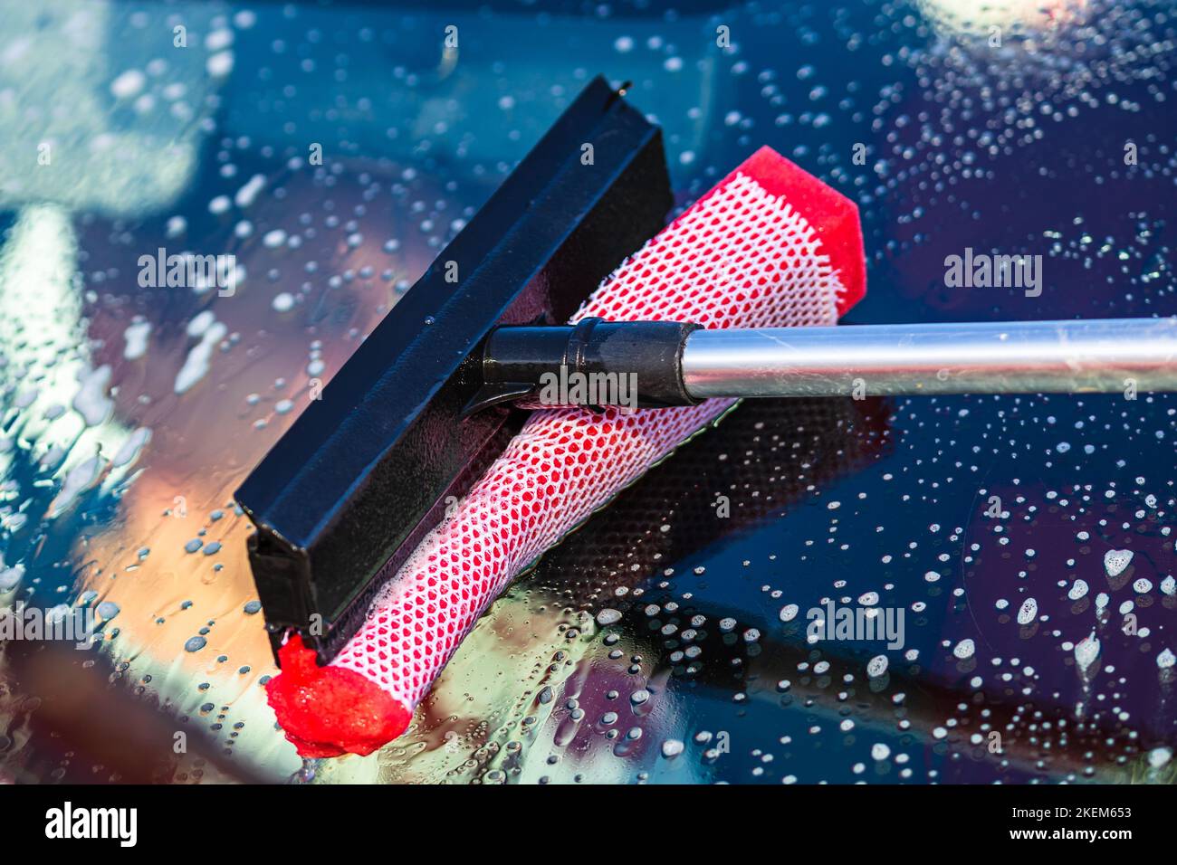 Washing and cleaning the front window of a car with mop in self service ...