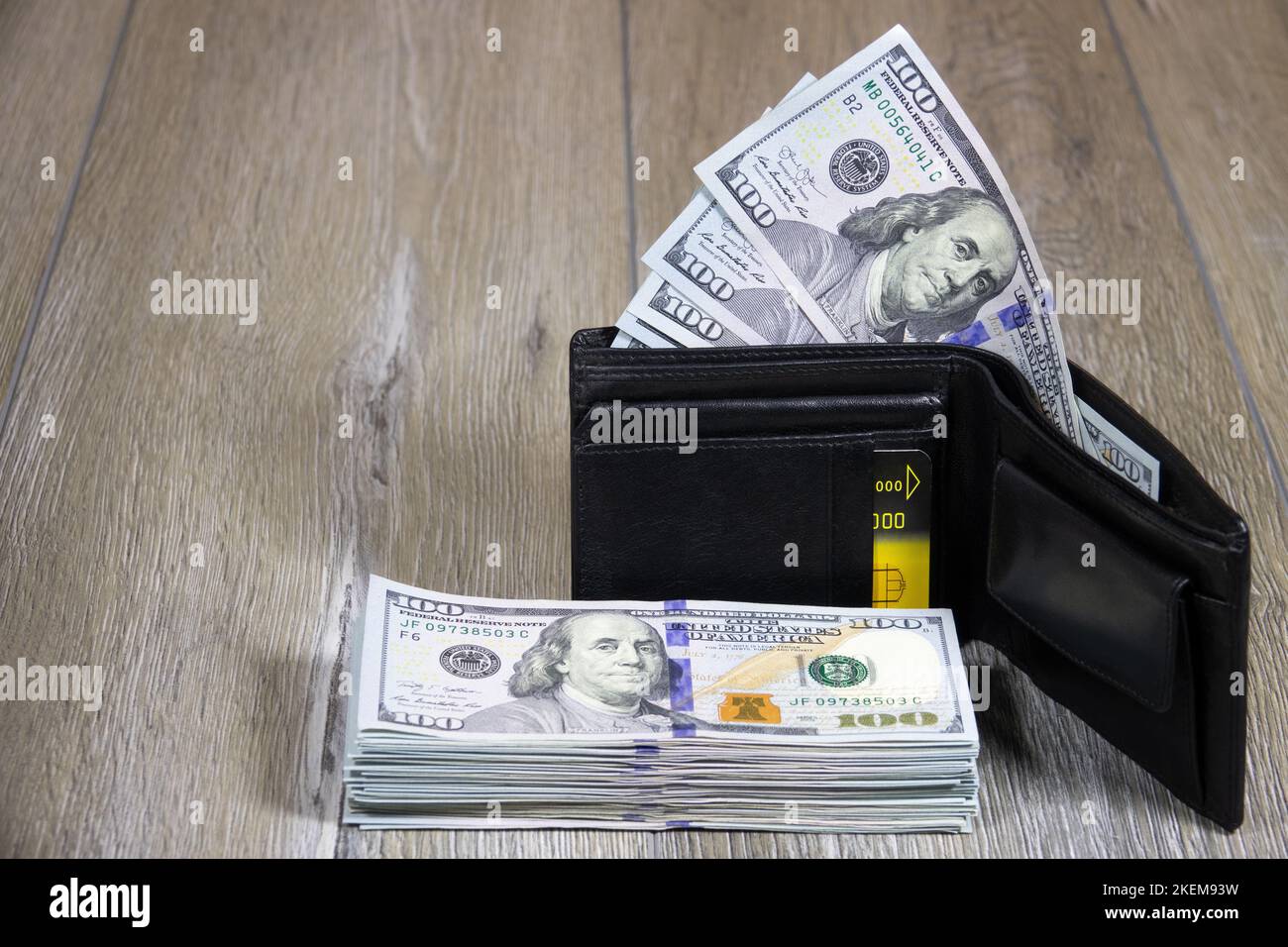 Black leather wallet with dollars and a credit card inside on a gray ...