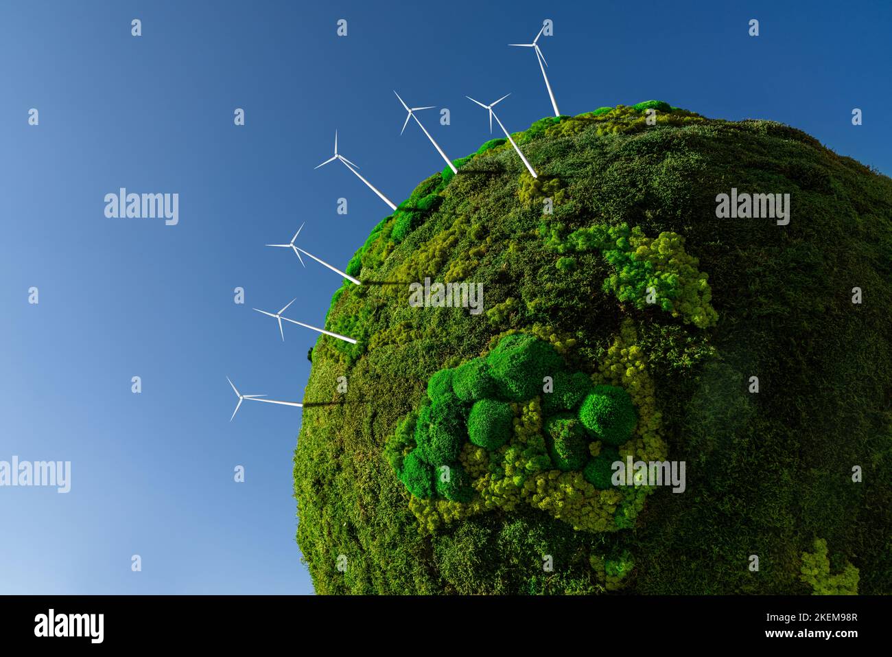 Model of the green planet Earth from moss with wind turbines. Symbol of ...