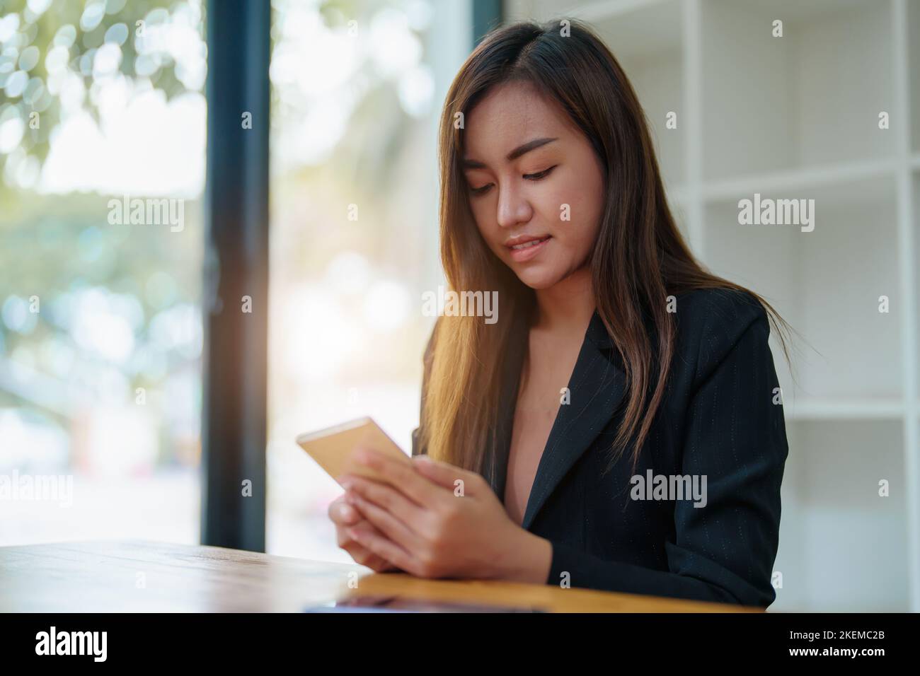 Portrait of an Asian female employee wearing a formal suit using a ...