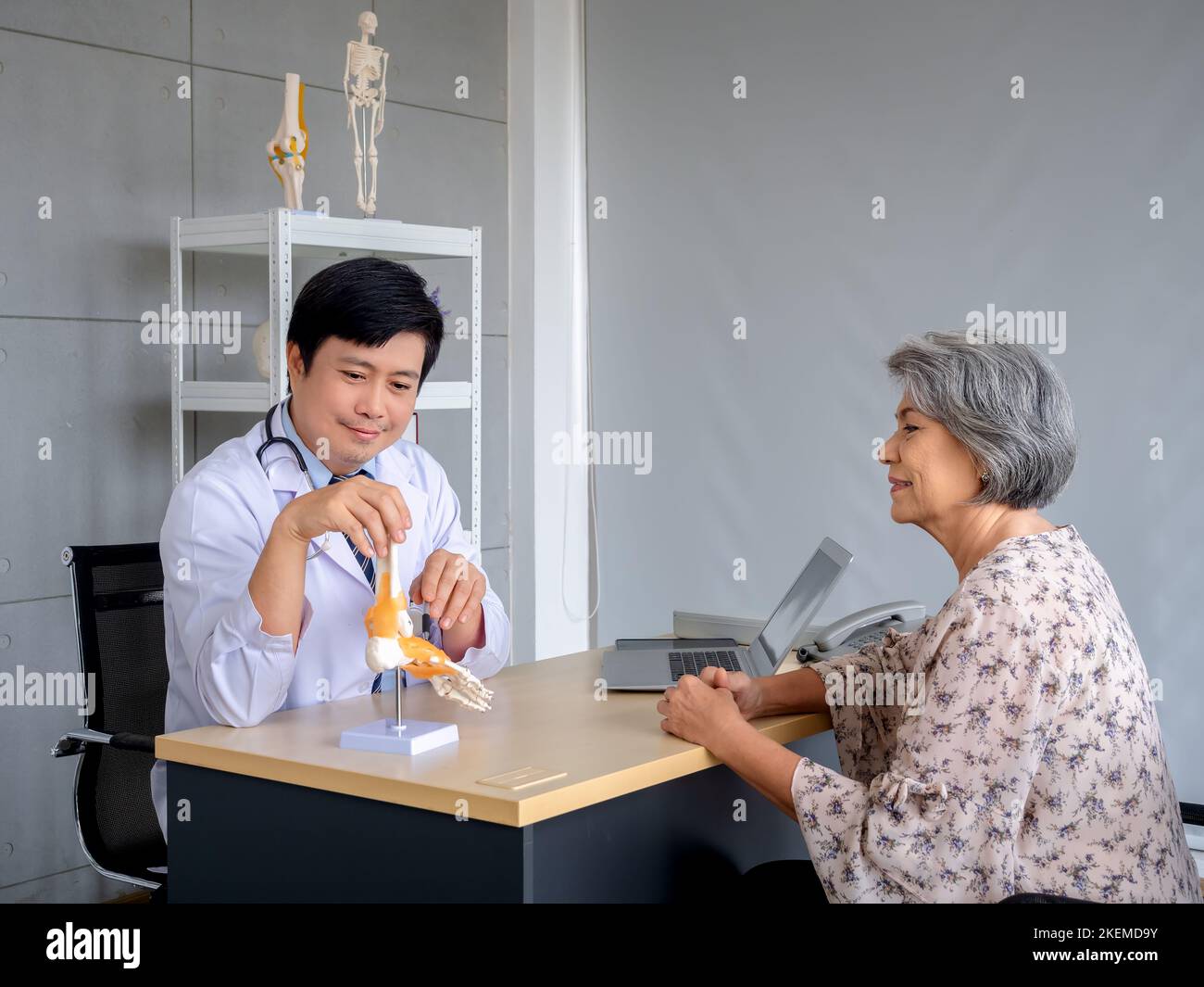 Smiling professional Asian man orthopedic doctor pointing to foot ...