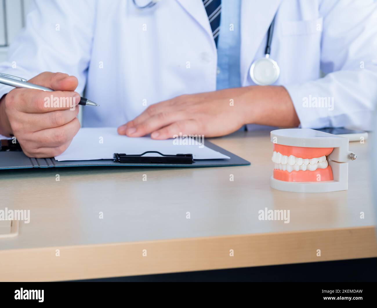 Close up a tooth model on desk while dentist make writing with a ...