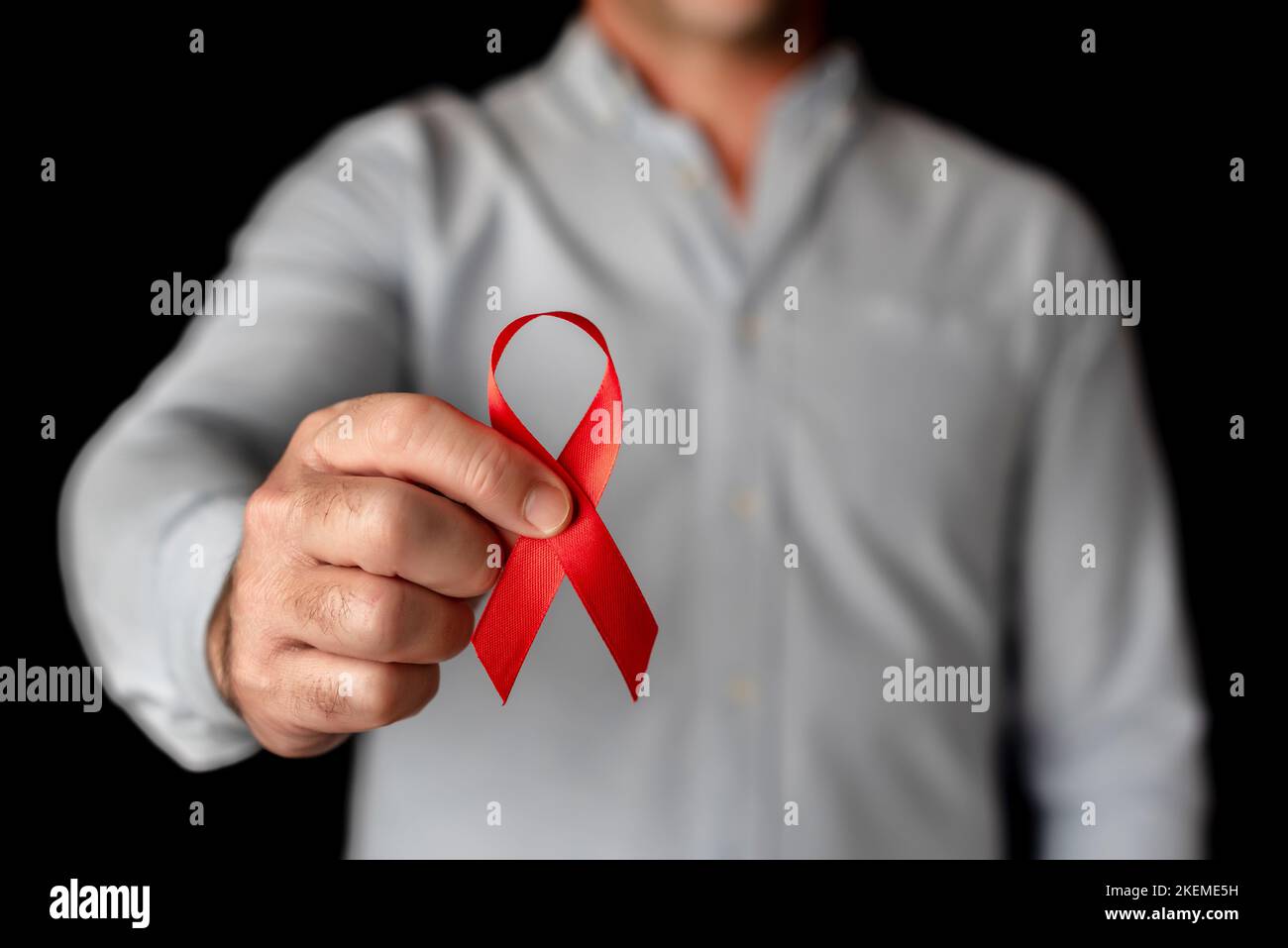 A man shows the camera a red ribbon in support of World AIDS Day on a ...