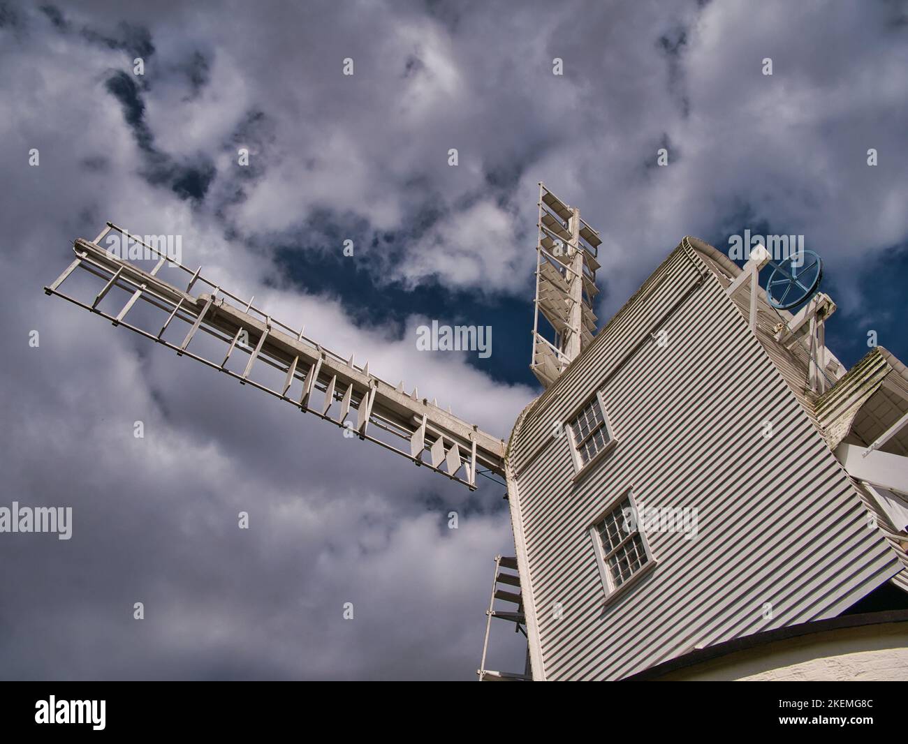 A view upwards of the side and sails of a white wooden windmill of ...