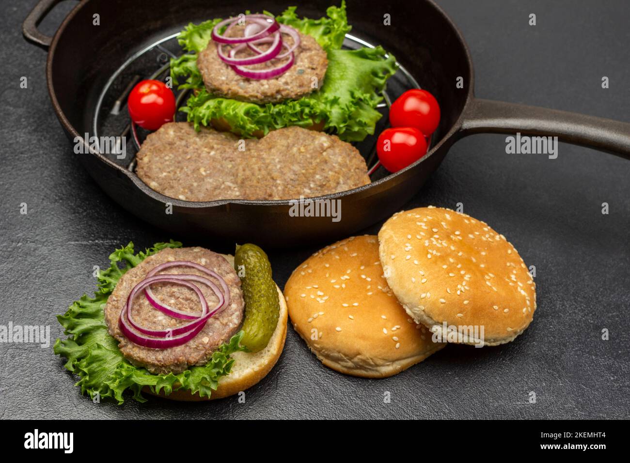 Grilled burger, pickle, onion and lettuce on round bun. Buns on the ...