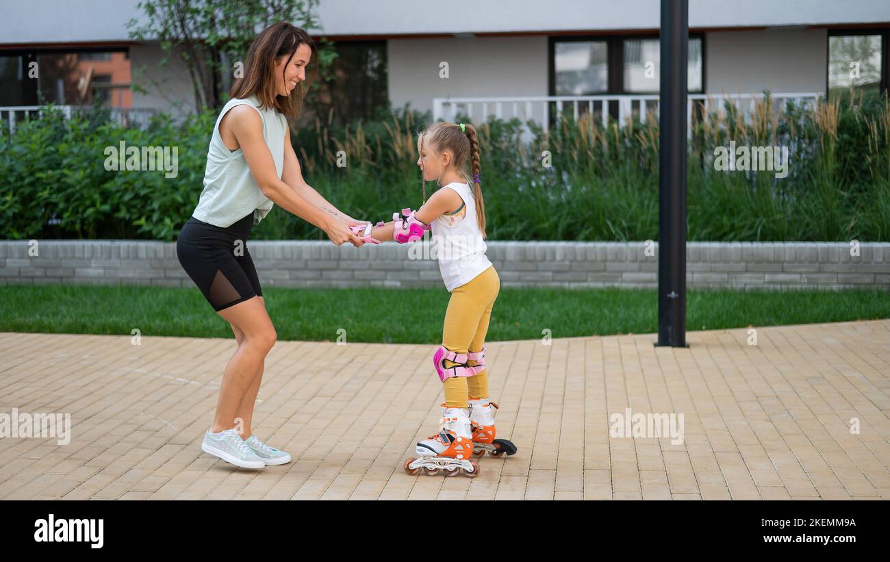 Mother helps daughter learn to roller skate Stock Photo - Alamy