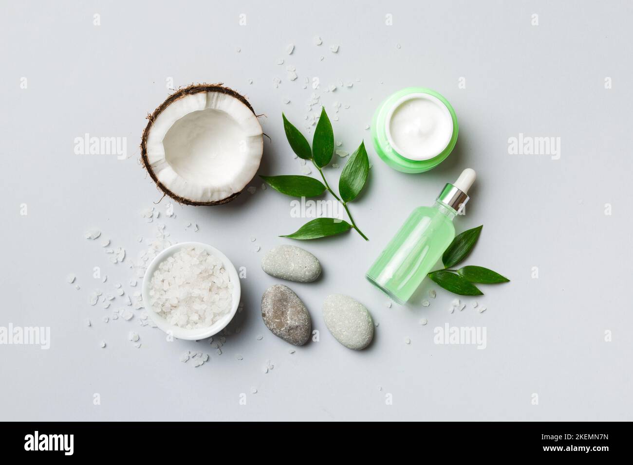 Coconut with jars of coconut oil and cosmetic cream on colored ...