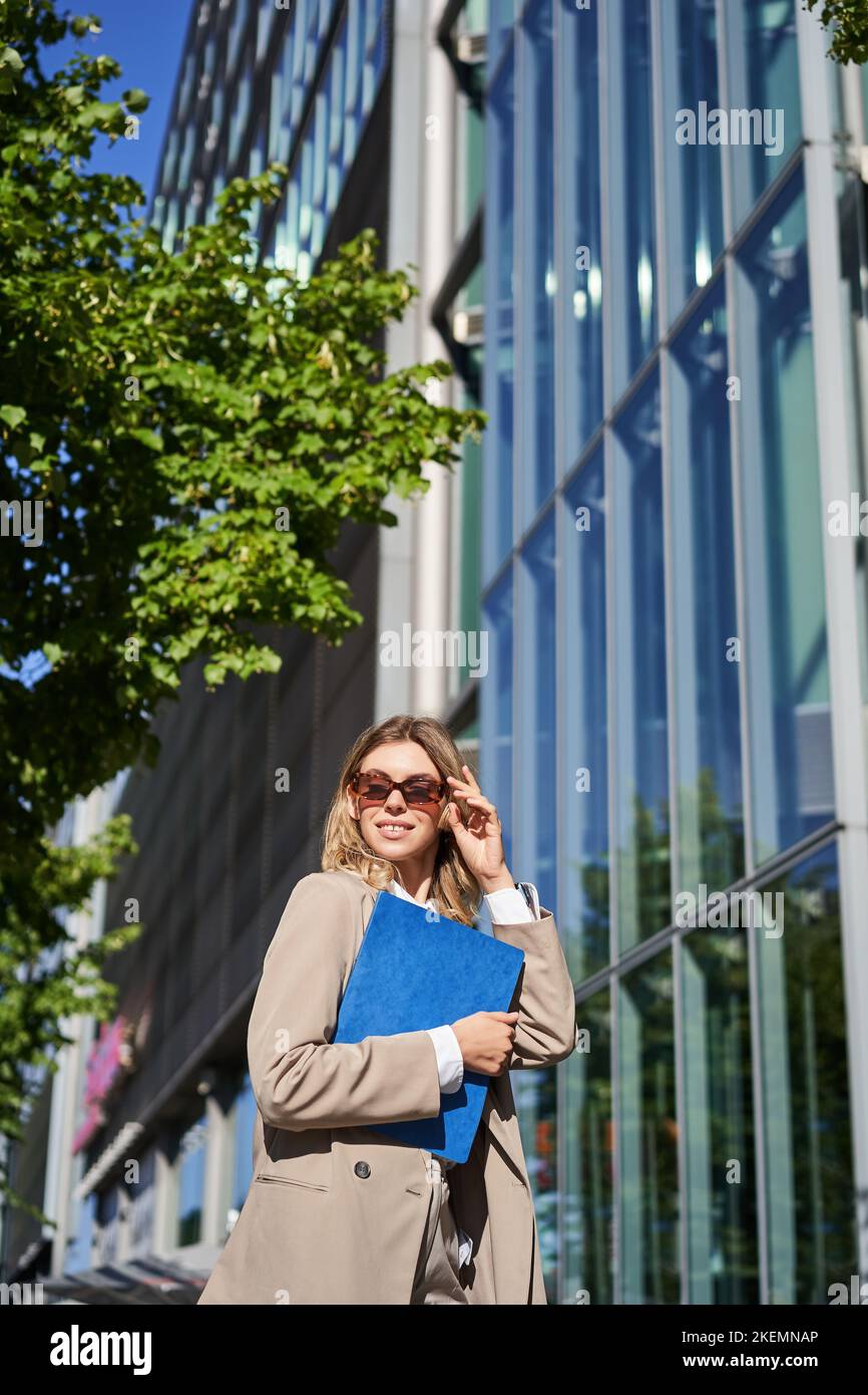 Portrait of confident saleswoman going to work, wearing sunglasses and ...