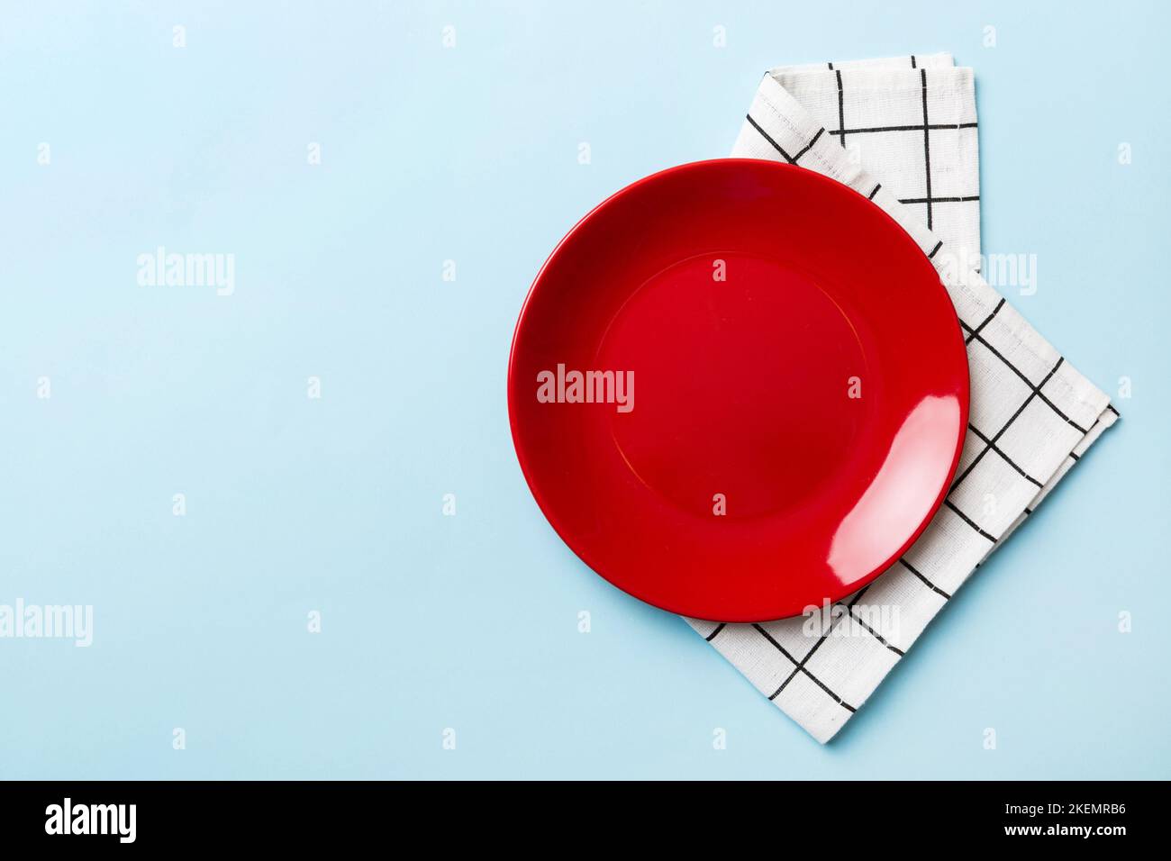 Top view on colored background empty round red plate on tablecloth for ...
