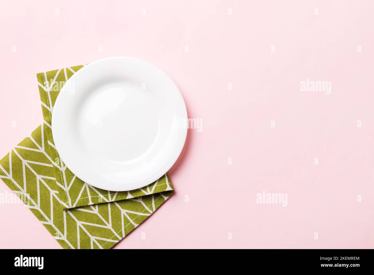 Top view on colored background empty round white plate on tablecloth ...