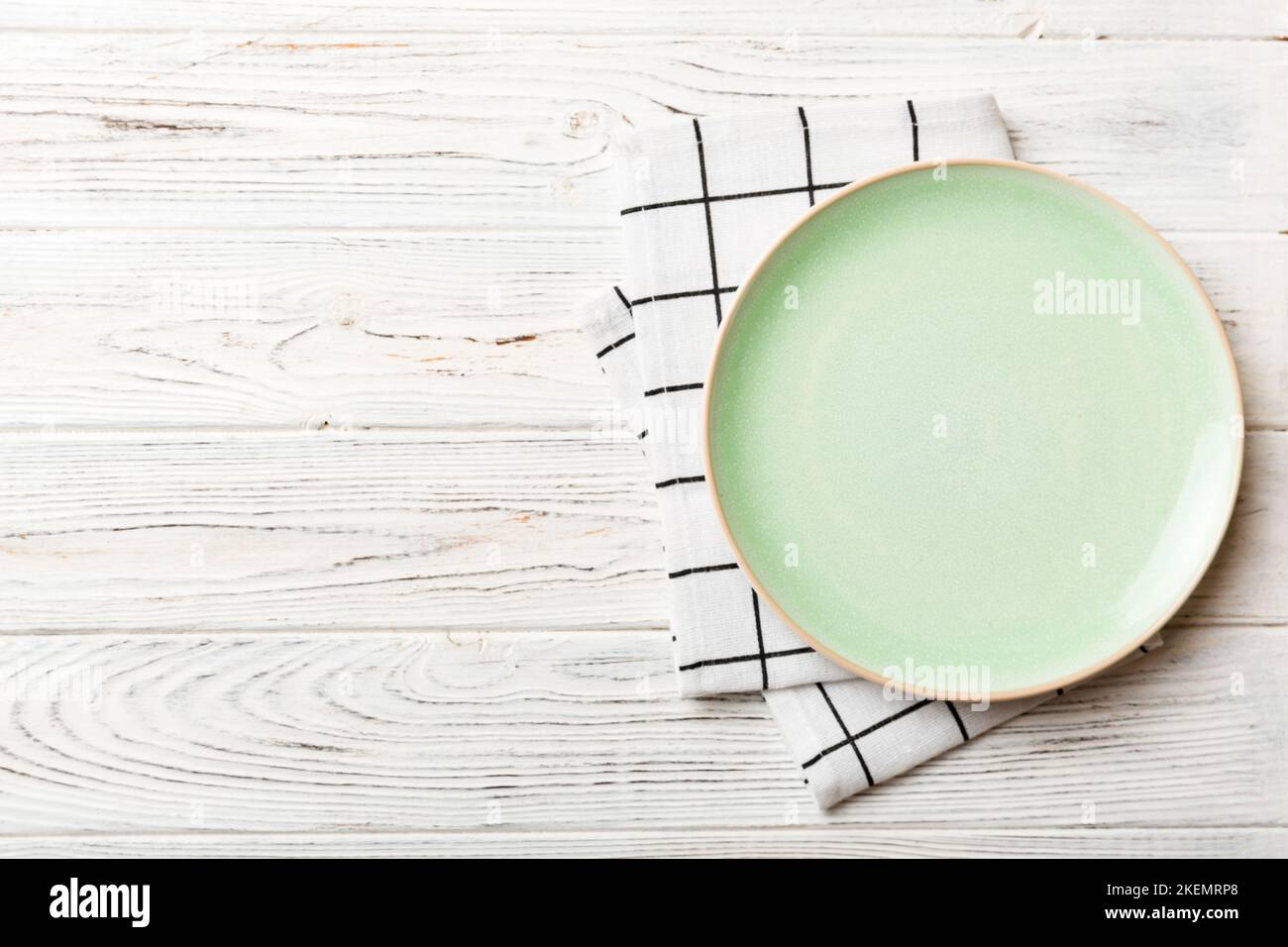 Top view on colored background empty round green plate on tablecloth ...
