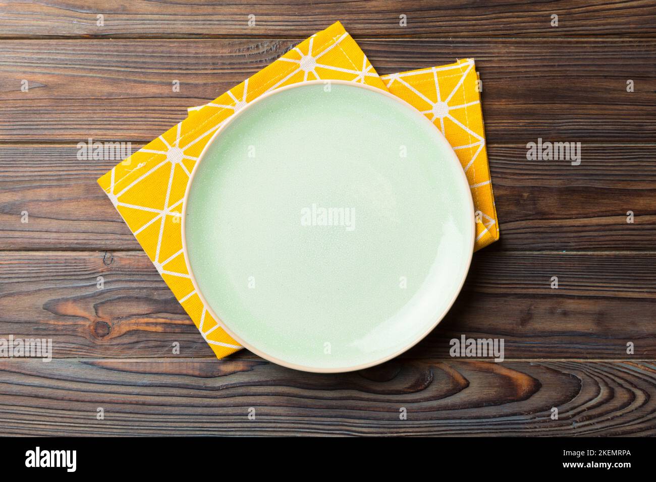 Top view on colored background empty round green plate on tablecloth ...