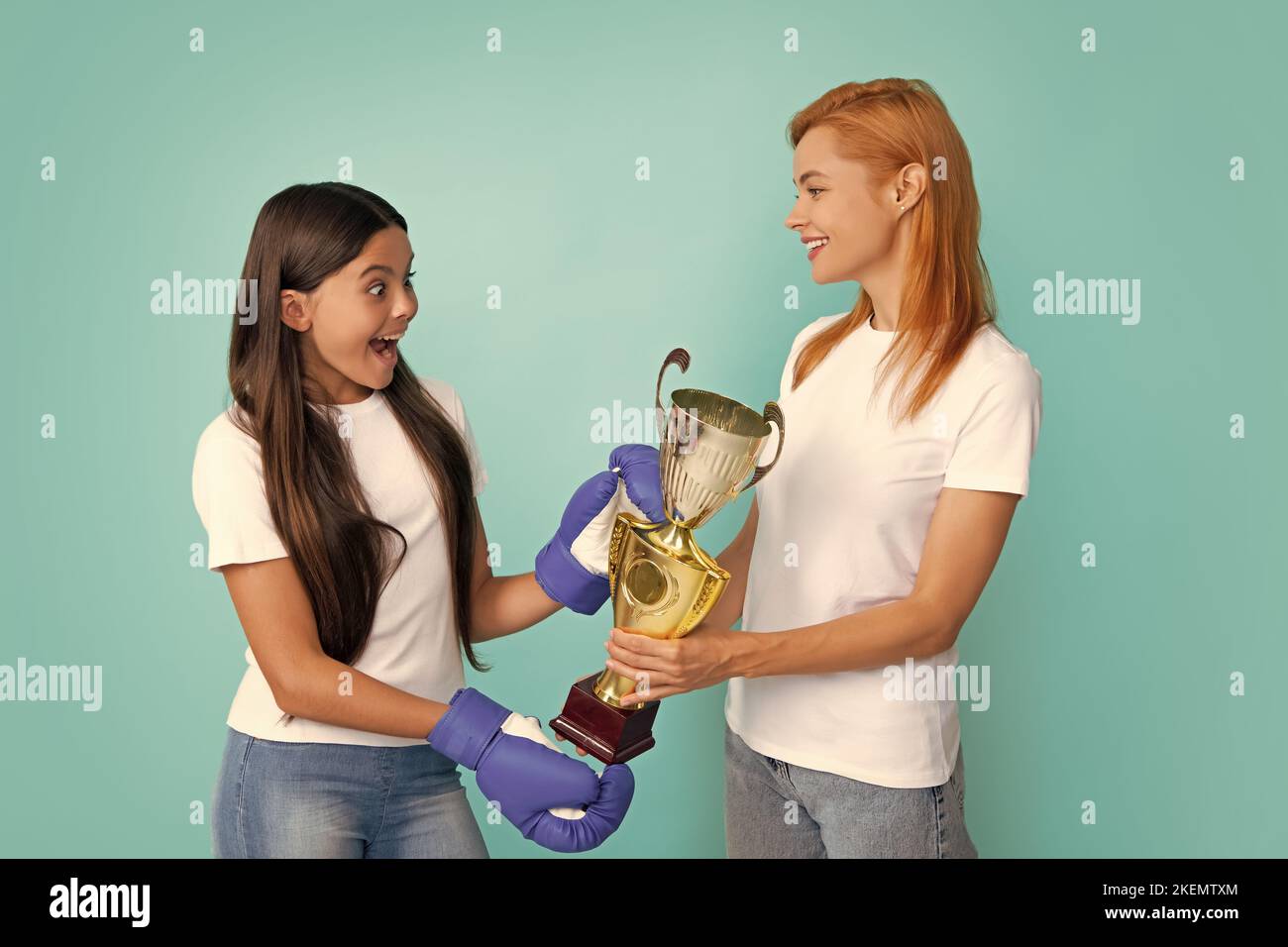 Mommy and teen daughter in boxing gloves holding winning prize, showing ...