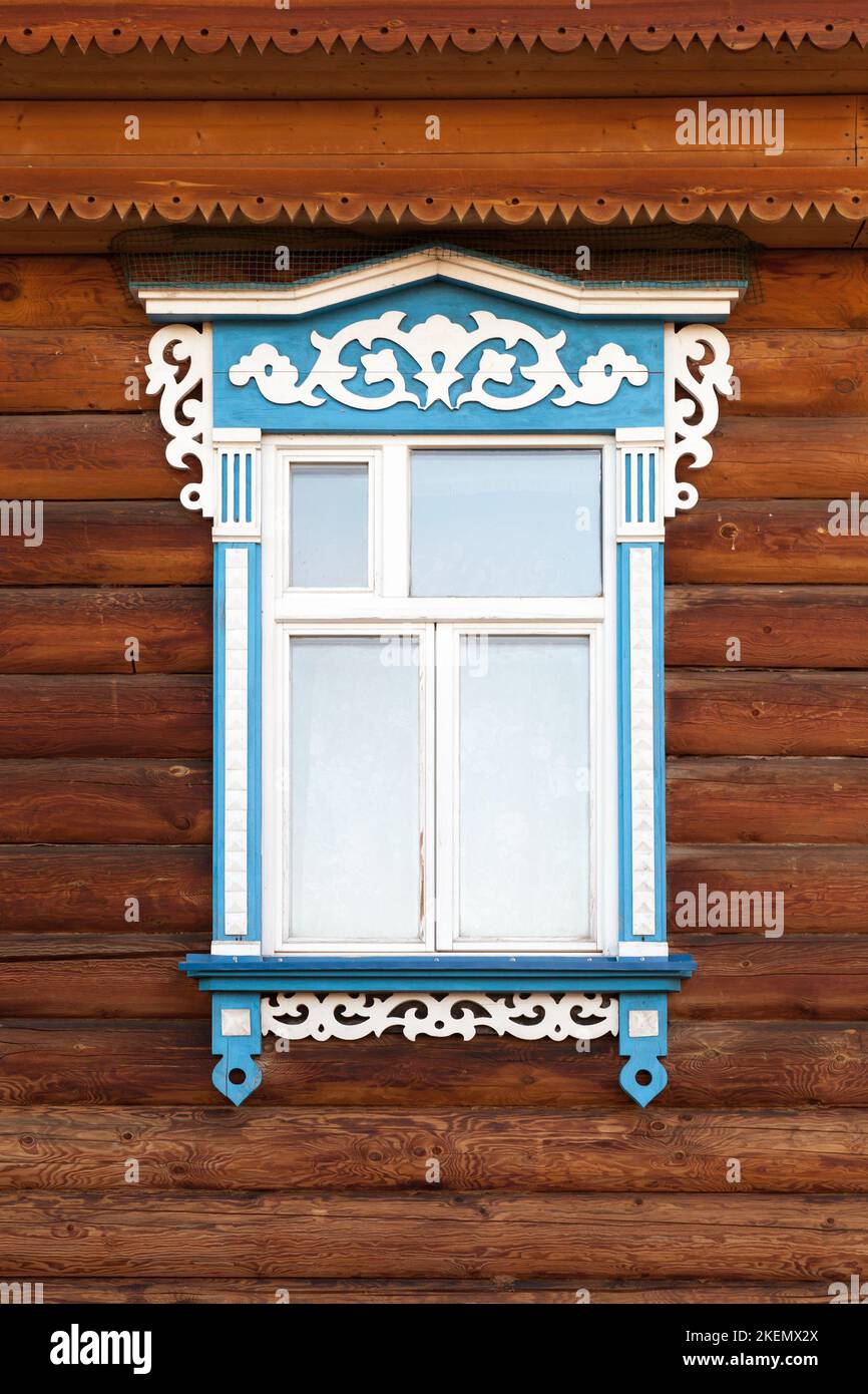 Window in blue white decorative frame in an old rural wooden house wall ...