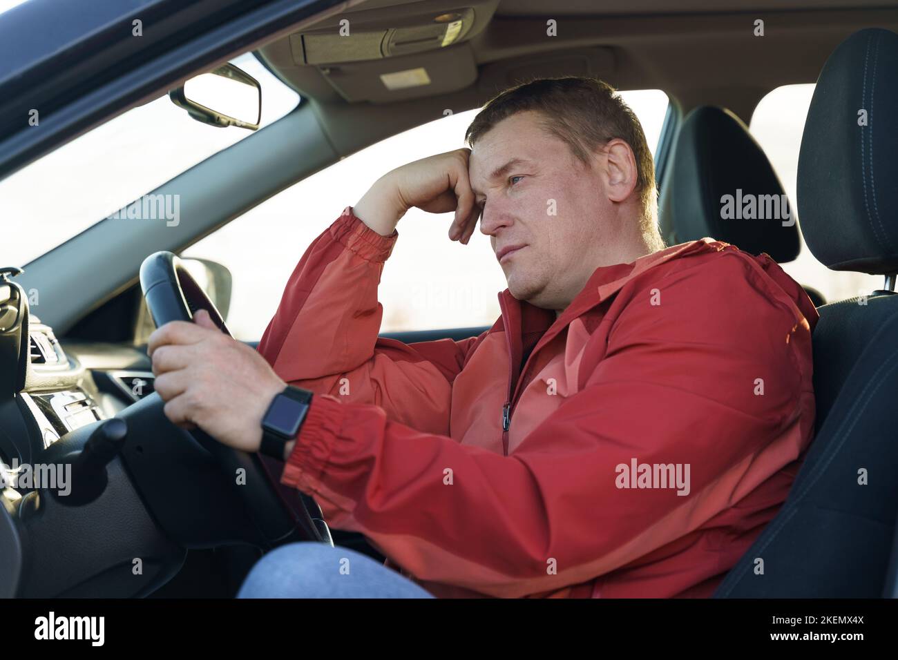 The driver is a man sitting behind the wheel, leaning on the steering ...