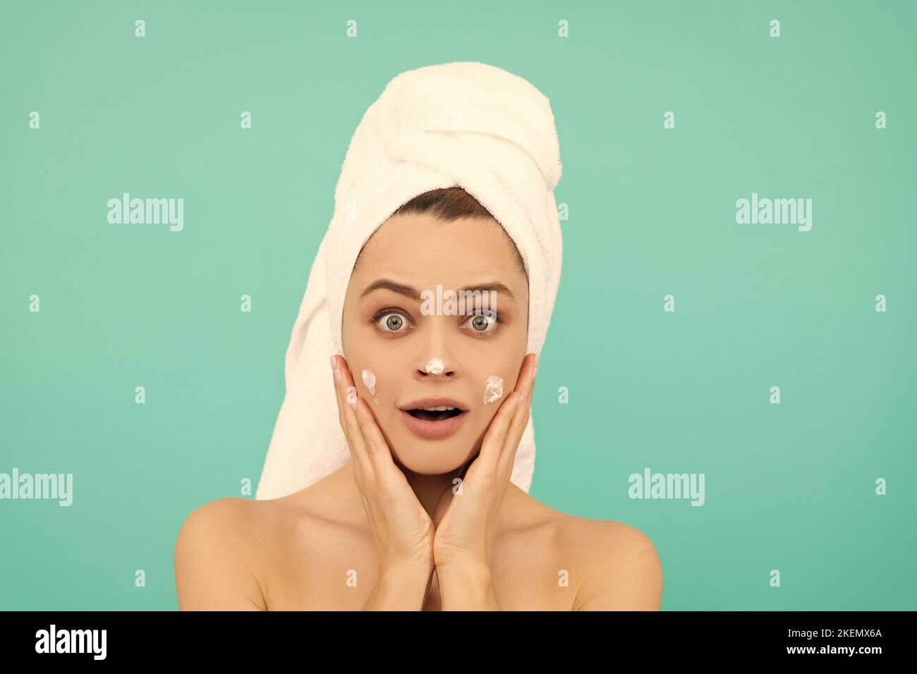 amazed young woman applying face cream on blue background Stock Photo ...