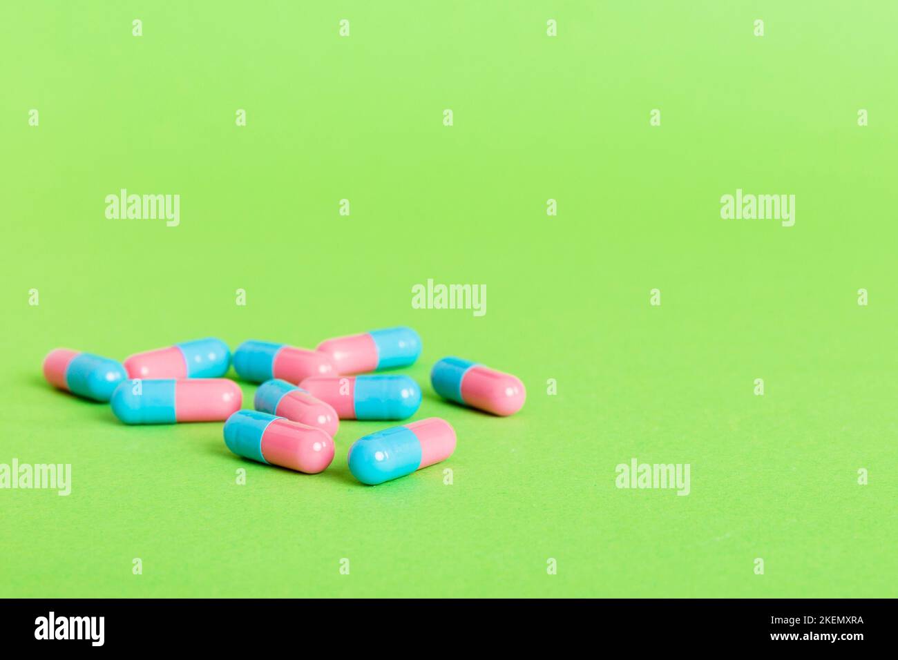 Heap of pink and blue pills on colored background. Tablets scattered on ...