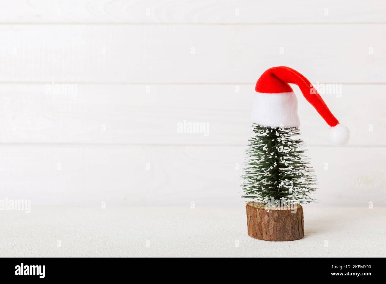 One small Christmas tree with santa hat on colored background. new year ...