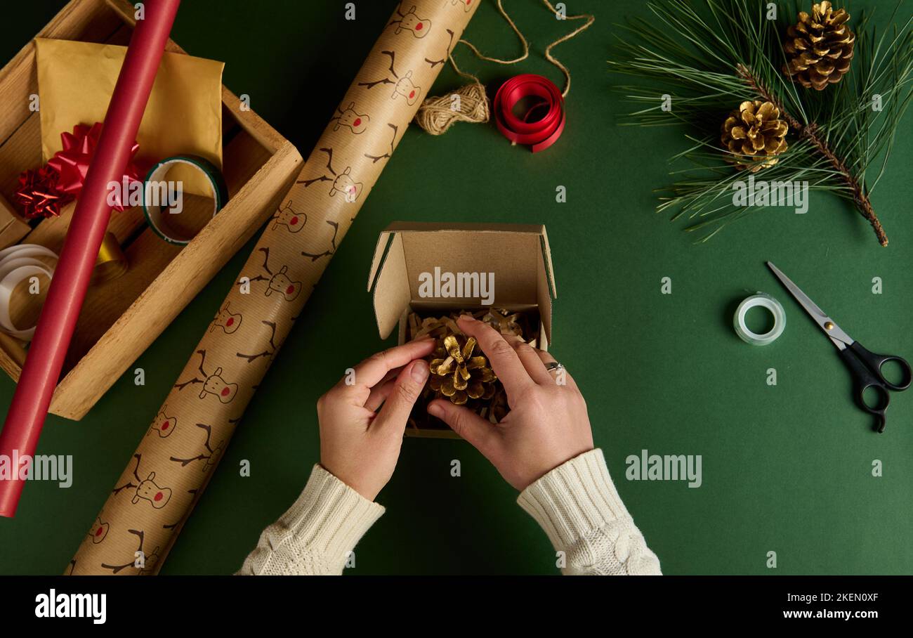 Directly above woman's hands putting a pine cone painted in gold, into ...