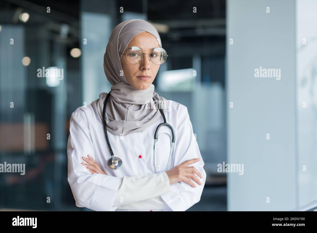 Portrait of a young Muslim woman doctor. She is standing in the hall of ...