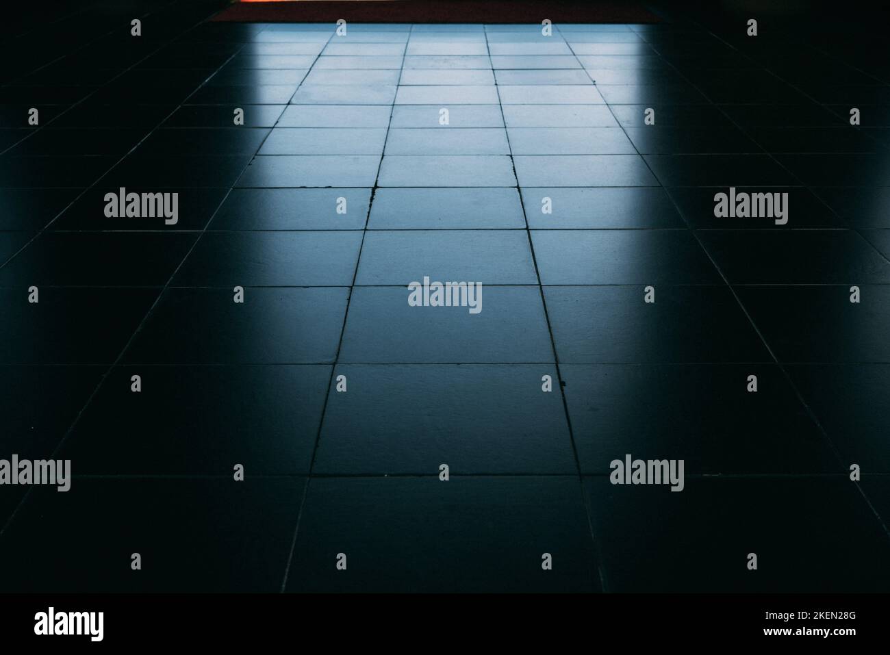 A dark tiled floor with a beam of light in the center Stock Photo - Alamy