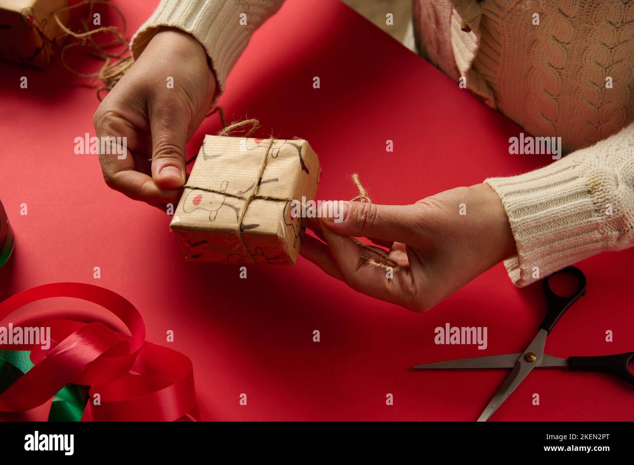 Craftswoman wraps Christmas present in a wrapping paper with deer ...
