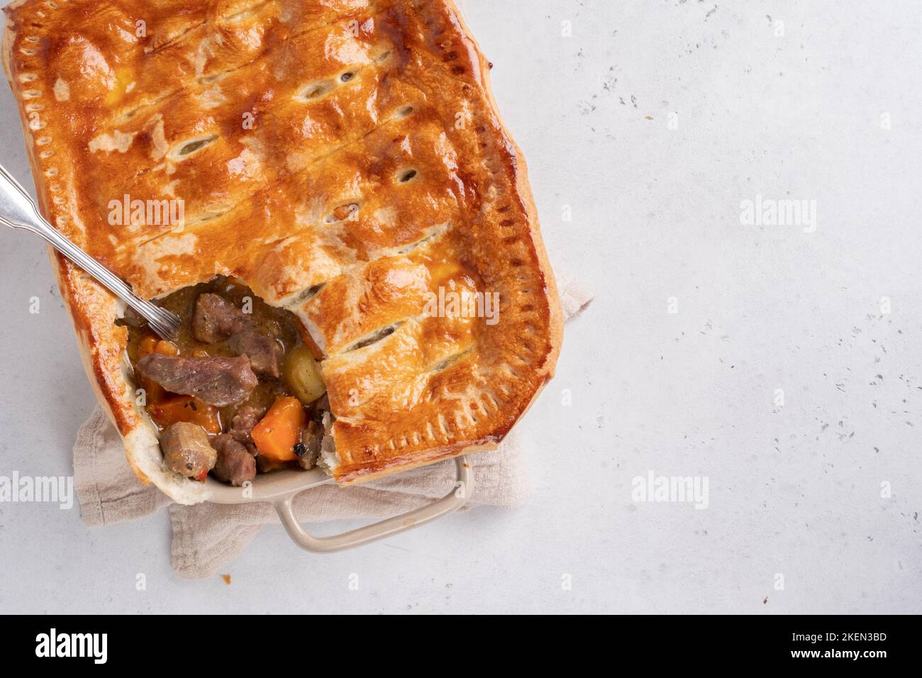 English beef steak pie with crispy puff pastry close-up in a baking ...