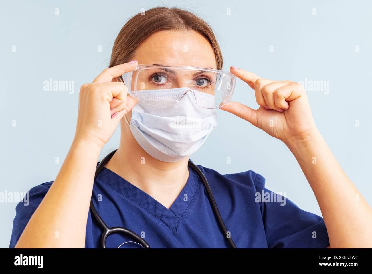 Female doctor putting on surgical face mask and medical goggle Stock ...