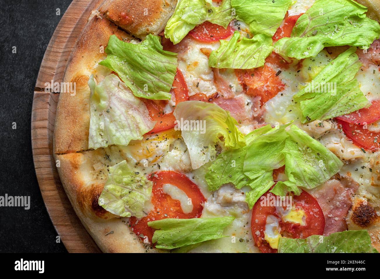 Pizza with chicken, vegetables, lettuce and bacon, on a wooden board ...