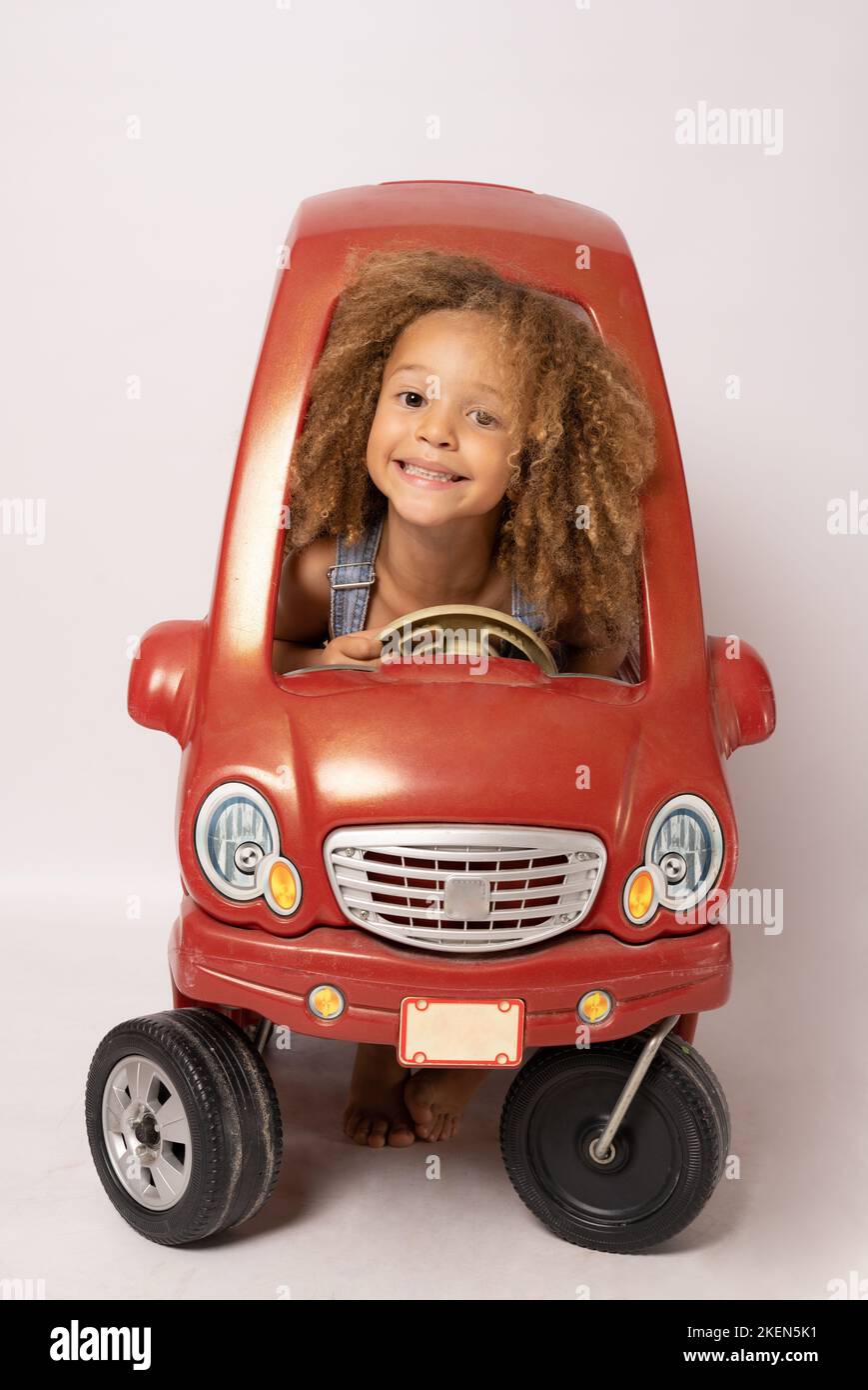 Cute little child girl driving children's electric toy car on white ...