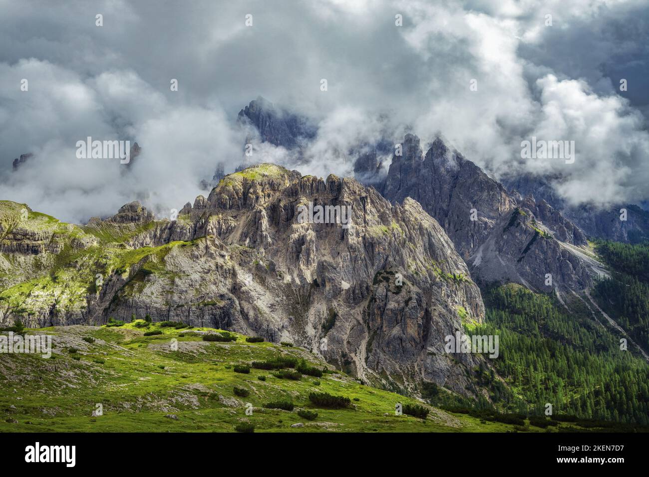 mountain landscape with rocks, green lawn and thunder clouds. Tre Cime ...