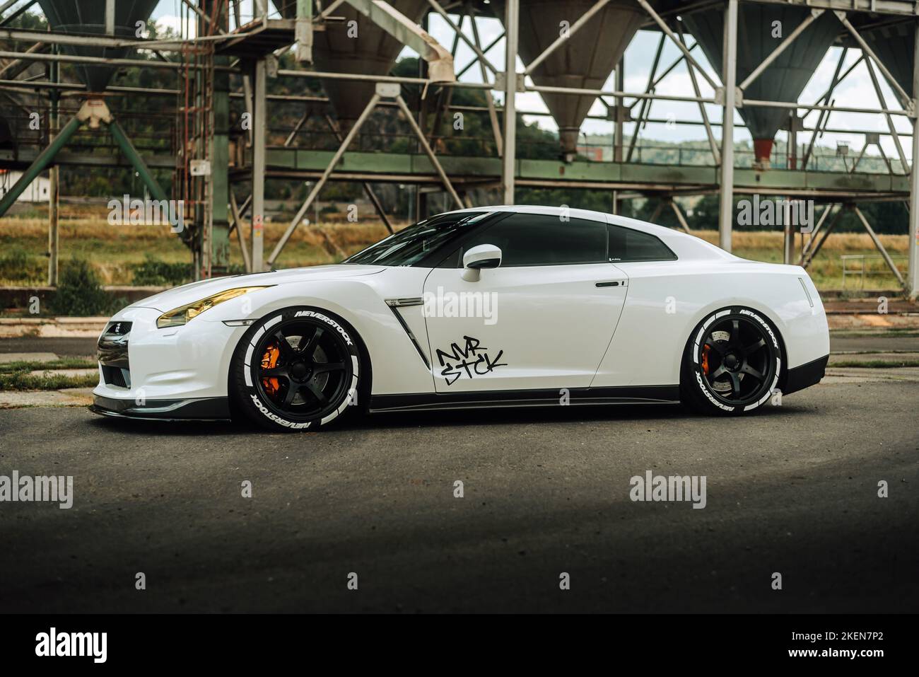 A beautiful shot of white nissan gtr in train field with industrial ...