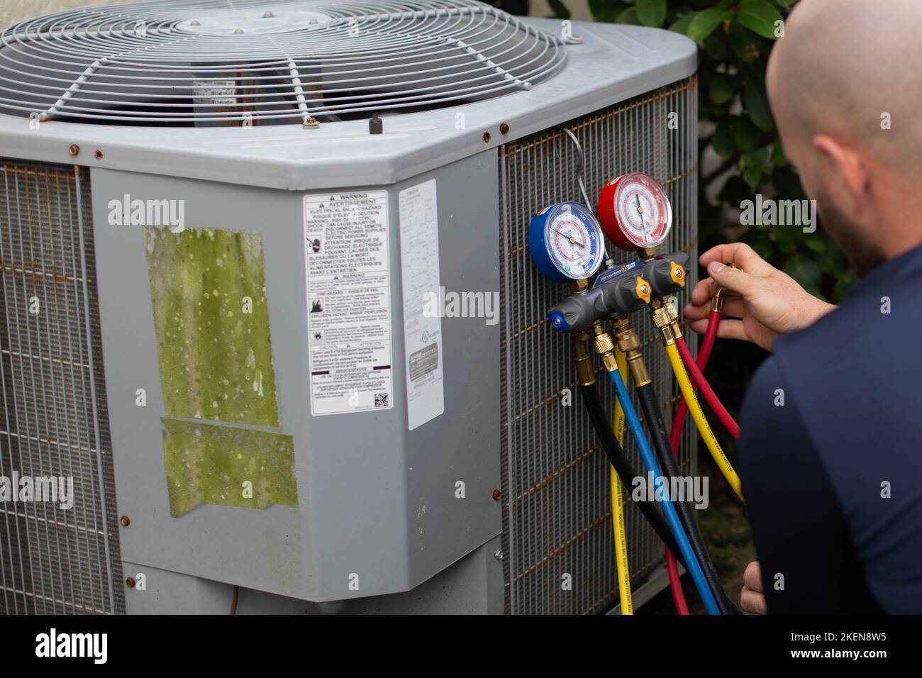 A closeup shot of AC Mechanic working on an AC outdoors air-conditioner ...