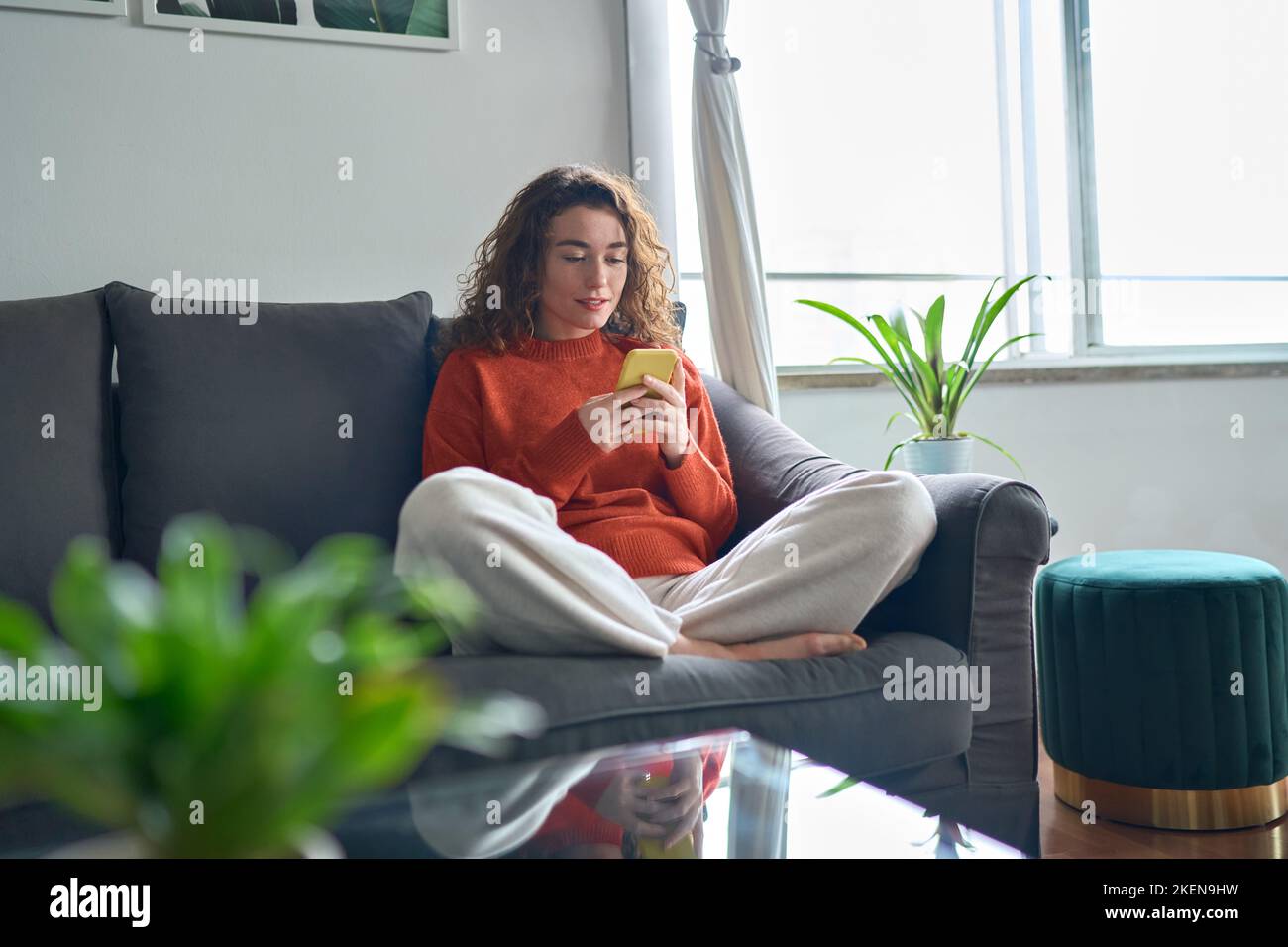 Relaxed young woman sitting on sofa using cell phone at home Stock ...