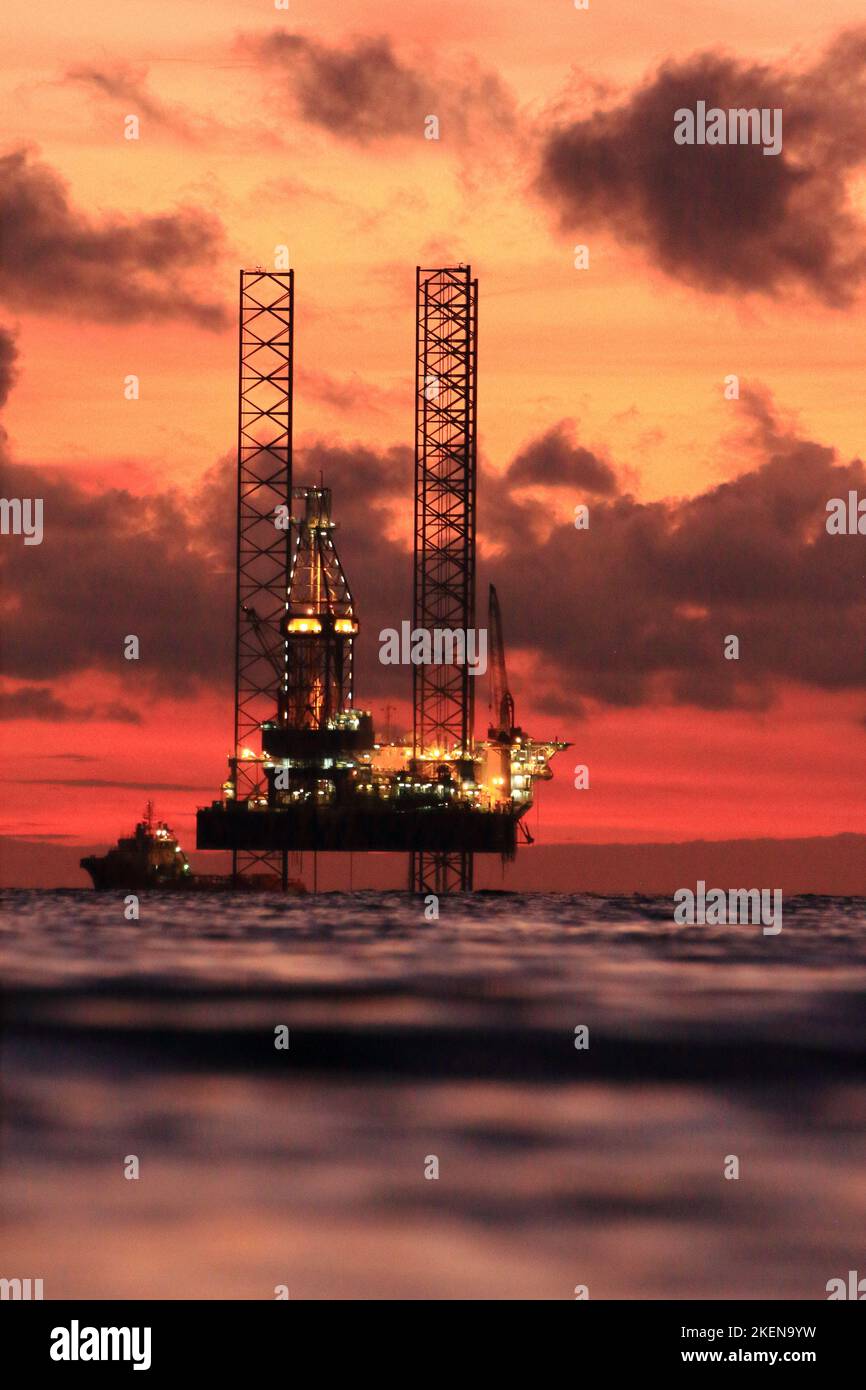 Silhouette of an offshore oil rig at sunset in the South China Sea ...