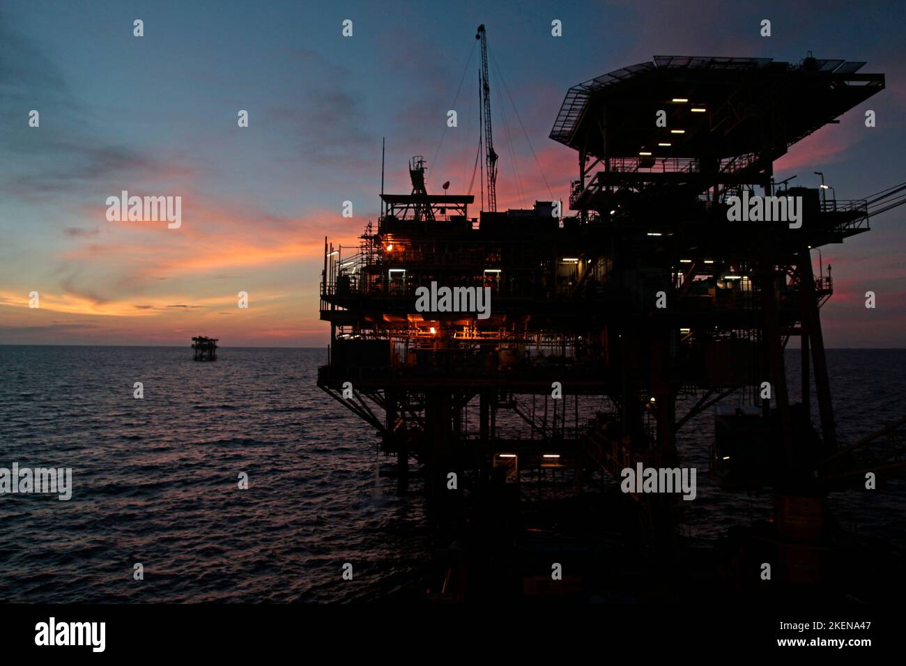 Silhouette of an offshore oil rig at sunset in the South China Sea ...