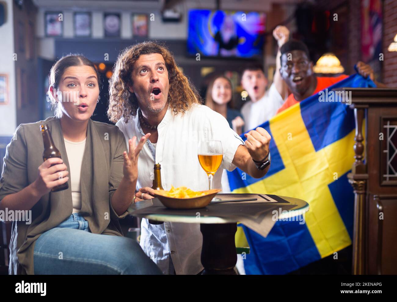 Emotional diverse soccer fans with flag of Sweden with glasses of beer ...