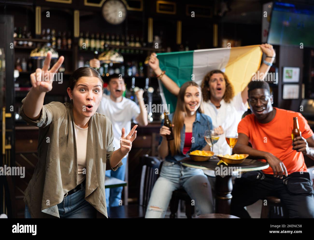 Excited young female fan rooting for favorite Irish team in sports bar ...