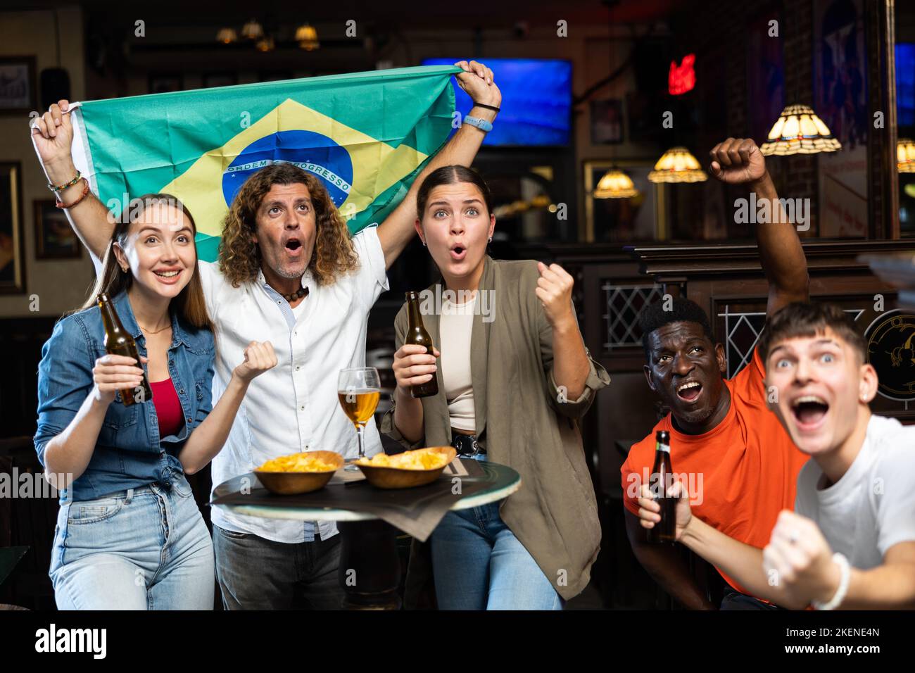 Emotional football fans cheering for favorite Brazil team in sports bar ...