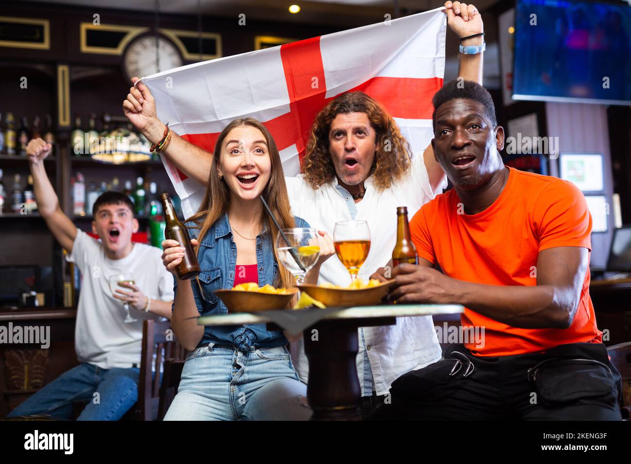 Excited diverse fans with flag of England with glasses of beer in the ...