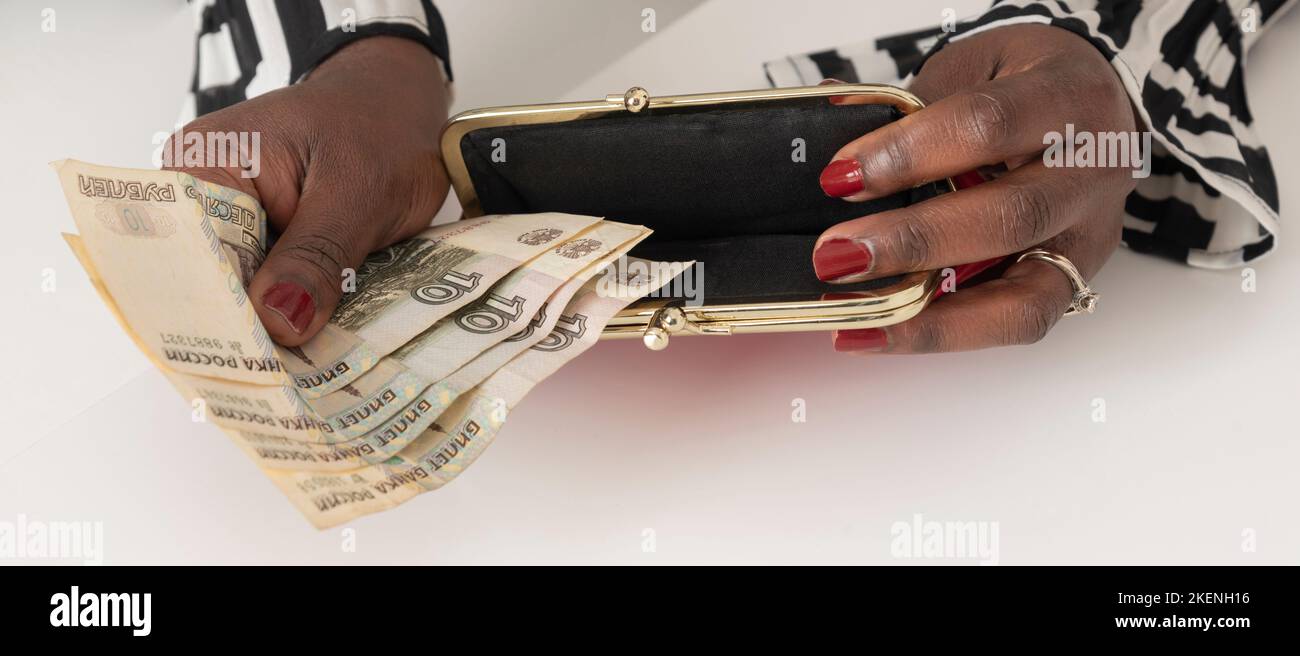 UK. 2022. Womans hands handling Russian banknotes against a white ...