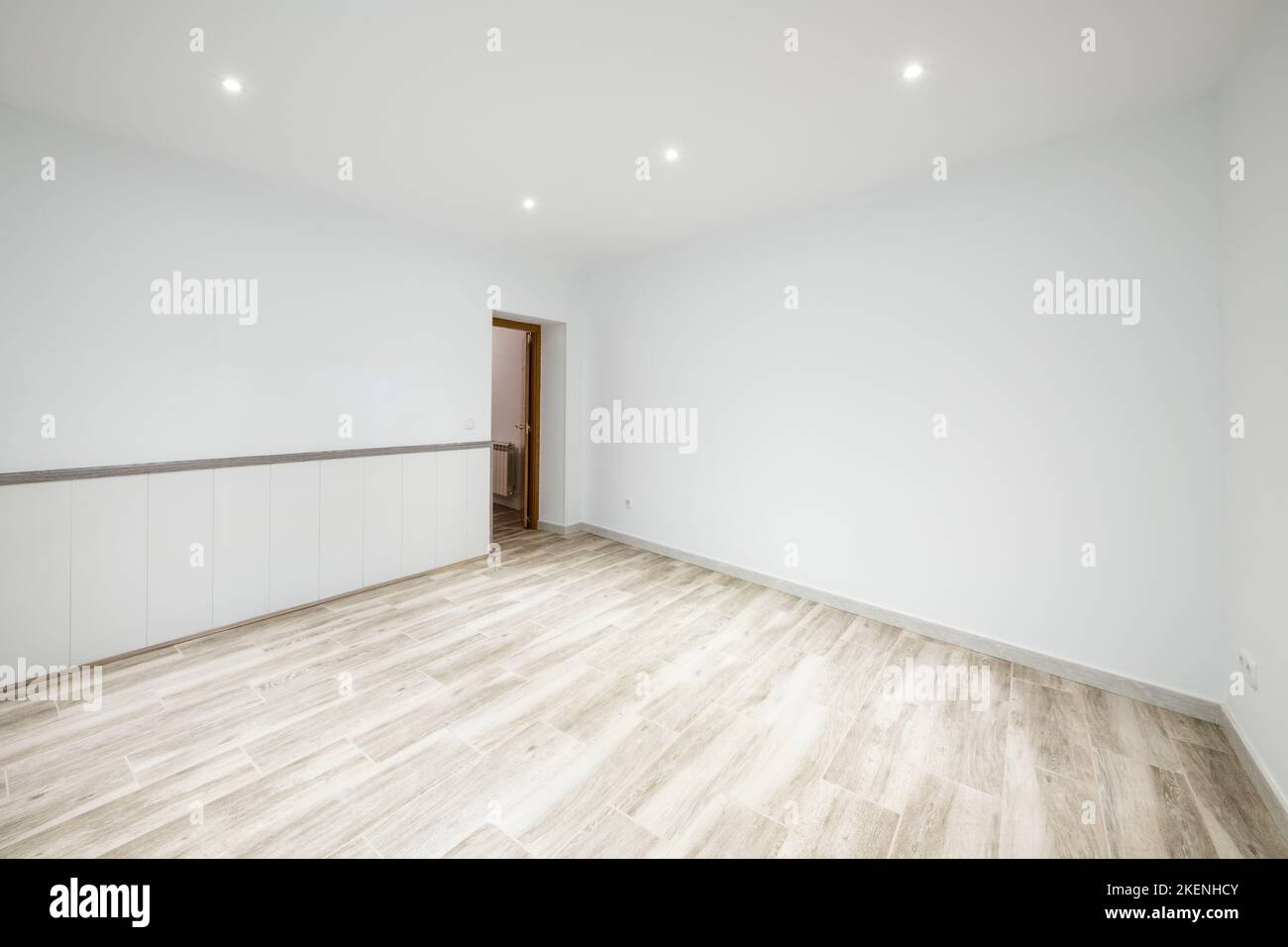 Empty room with wood-like stoneware floor, plain white walls and lamps ...